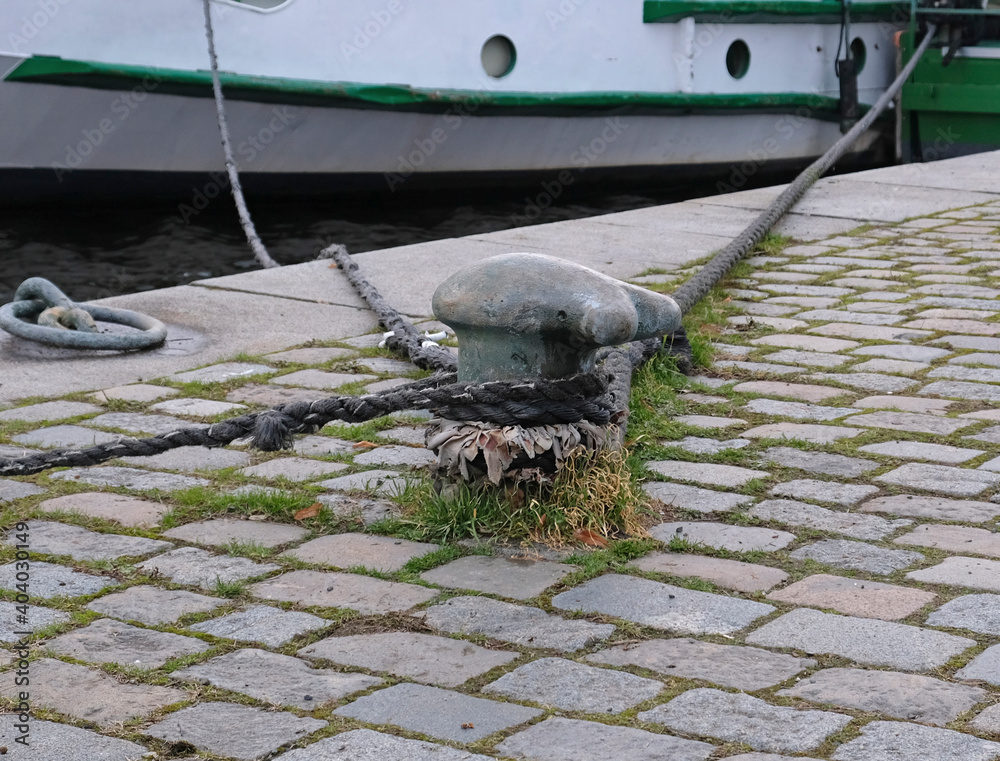 Rope for mooring a vessel is adhered to a pier. Rusty metal parking ...