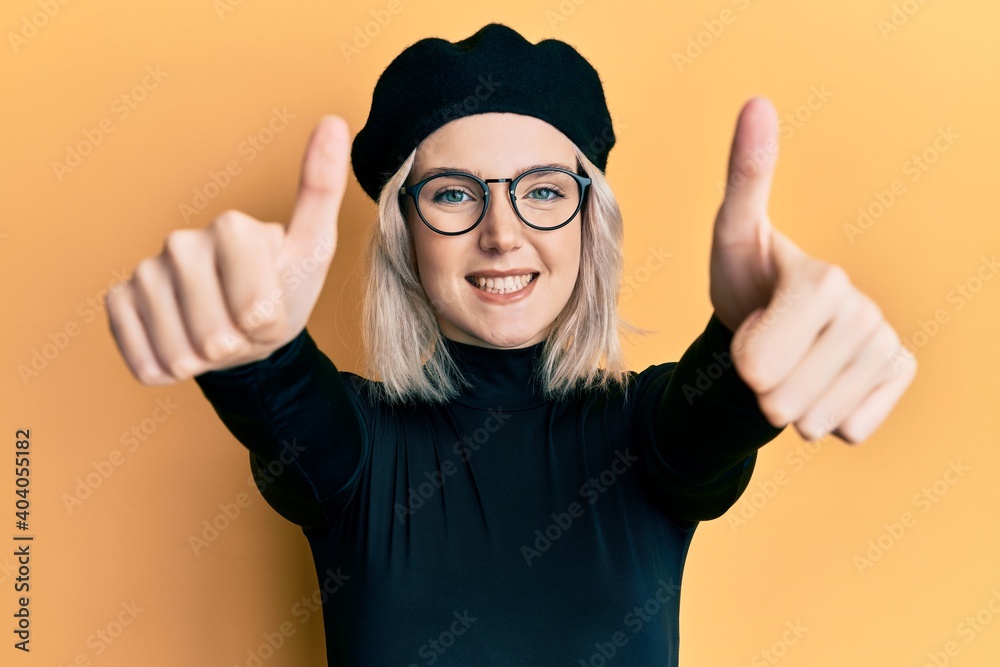 Young blonde girl wearing french look with beret approving doing ...