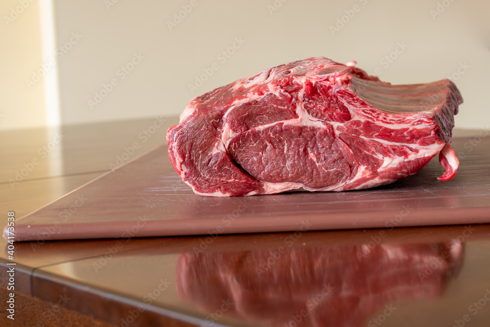 A large raw beef prime rib roast seasoned on a white plastic cutting ...