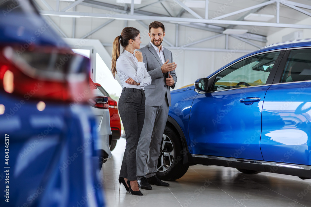 Smiling friendly car seller talking to a woman who wants to buy a car ...