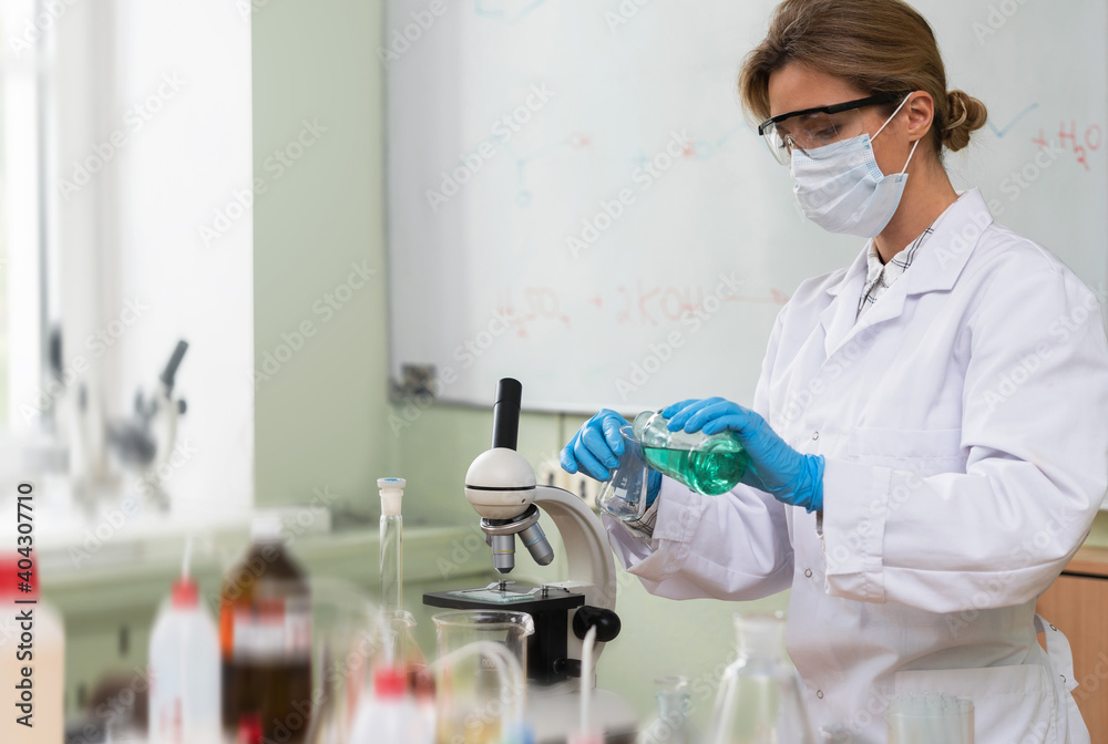 Scientist pouring substance from into Erlenmeyer flask in a laboratory ...
