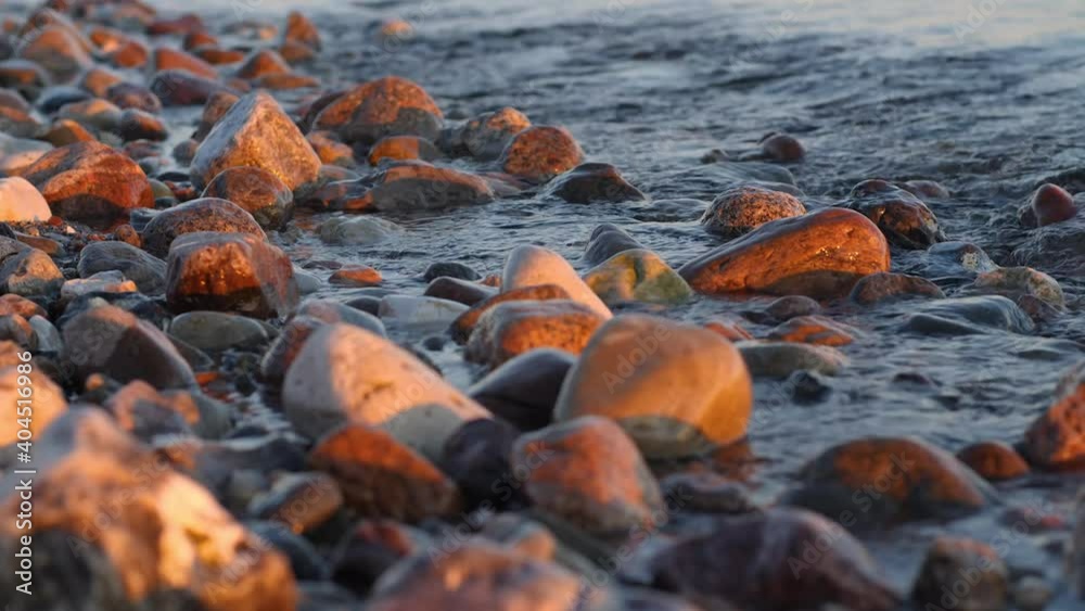Rocks and pebbles on the beach being watered as the waves wash in on ...