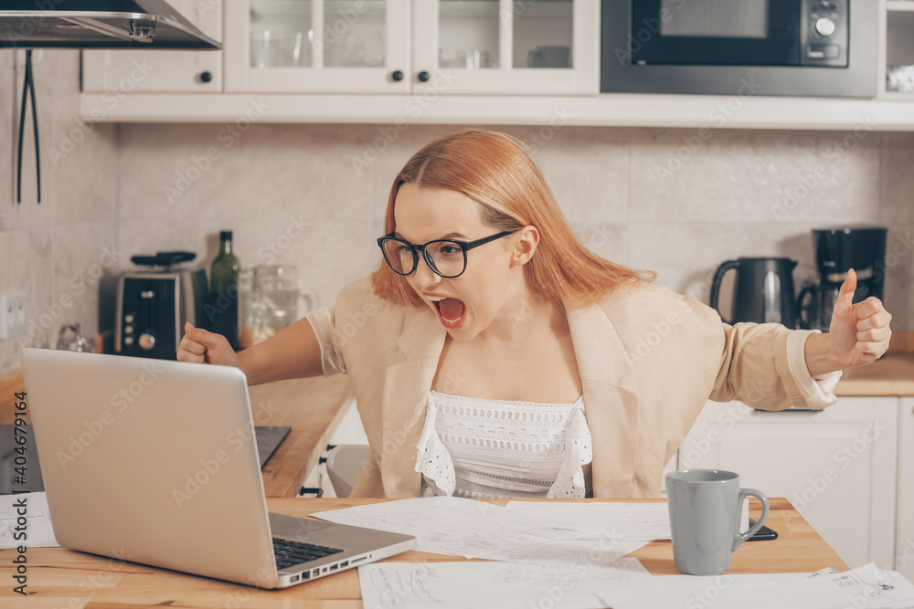 Woman behind laptop works from home. A beautiful blonde in a jacket and ...