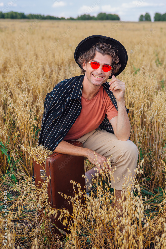 Tall handsome man with brown suitcase full of ears of oats sitting at ...