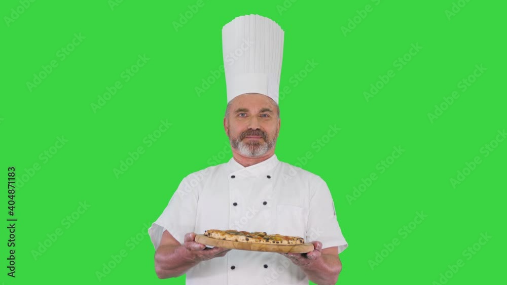 Senior male chief cook in uniform holding pizza on a Green Screen ...