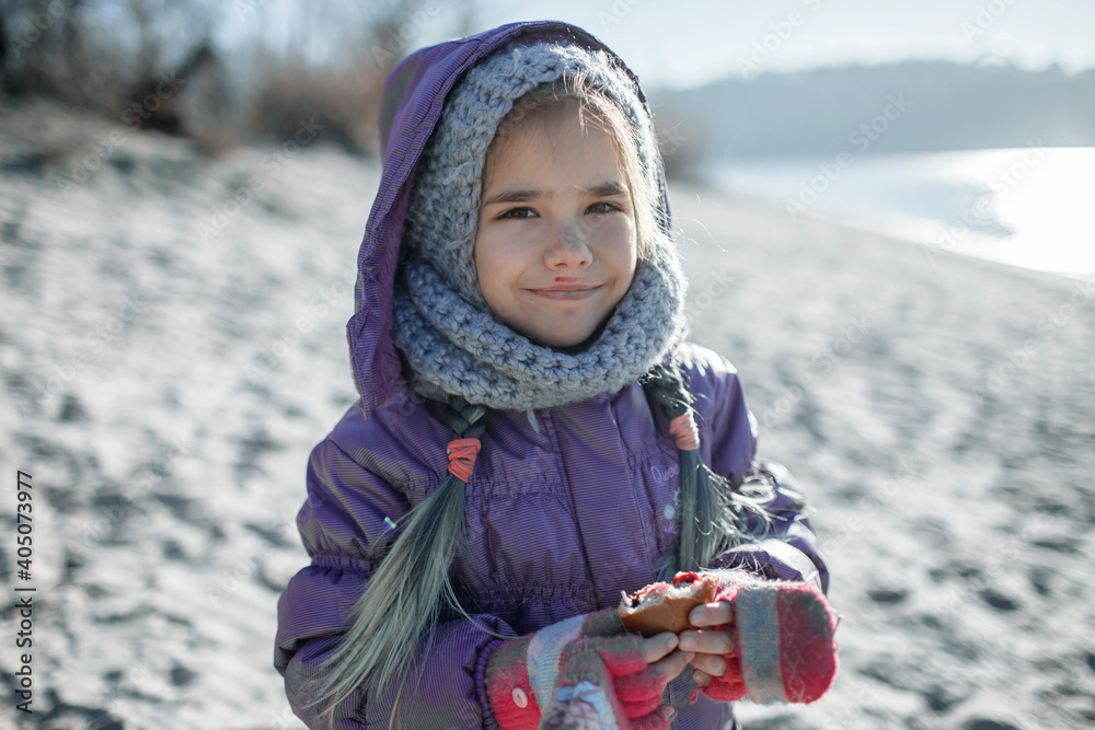 Kid walking at the beach in winter, drawing on sand and eating ...