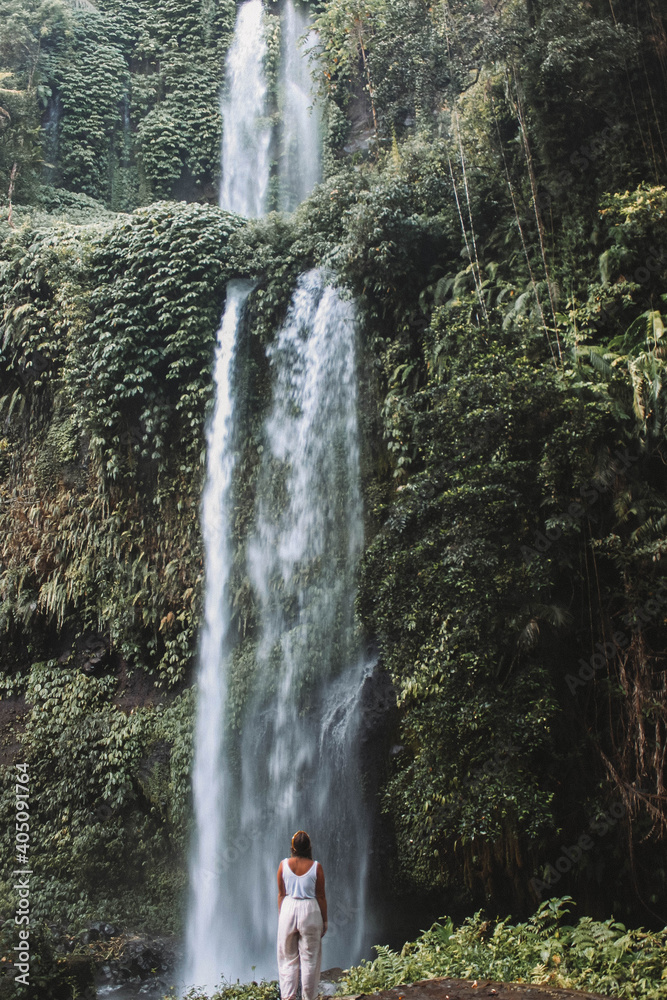 Woman standing and facing near waterfalls Stock Photo | Adobe Stock