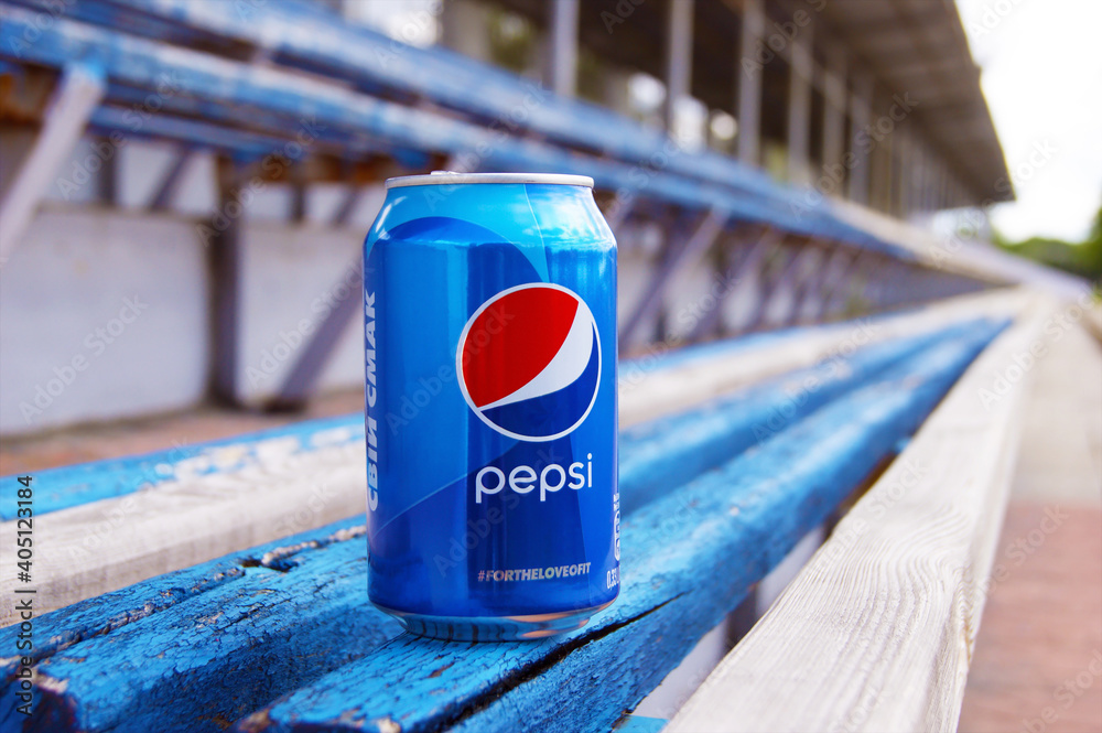 A metal bottle of Pepsi drink stands on a wooden bench in a small ...