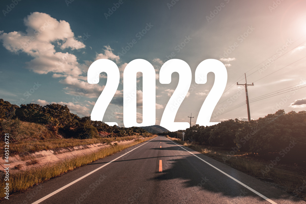 The word 2022 behind the tree of empty asphalt road at golden sunset ...