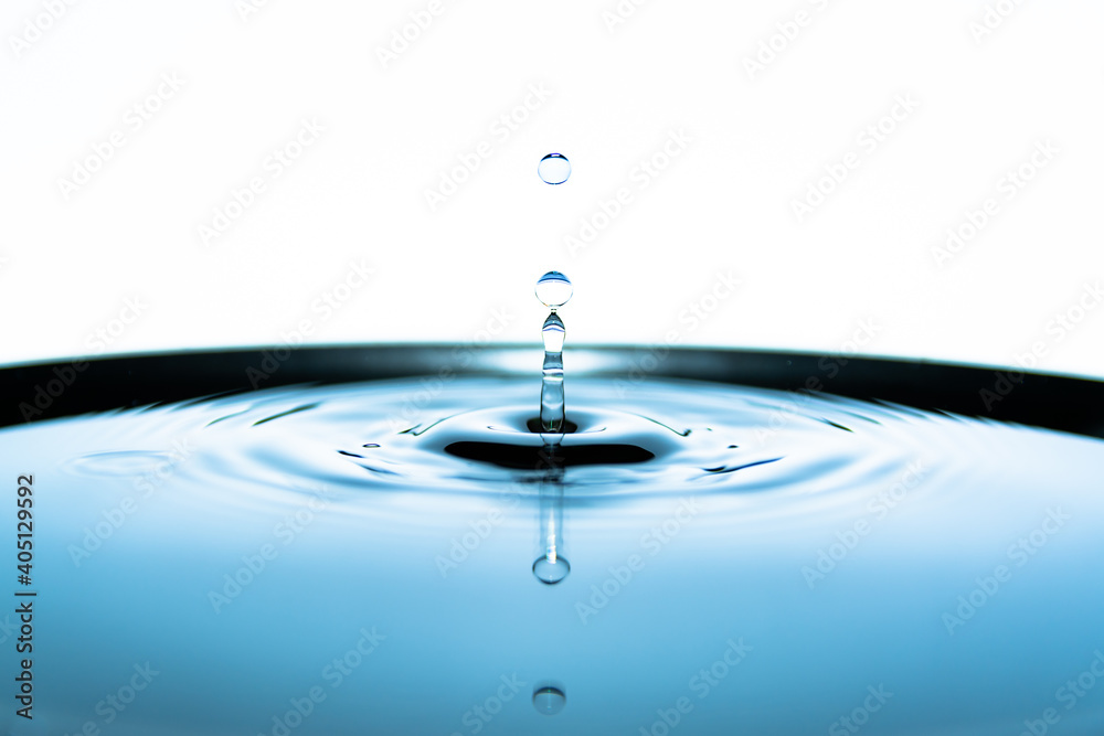 falling water drop hitting and reflecting from the surface of blue ...