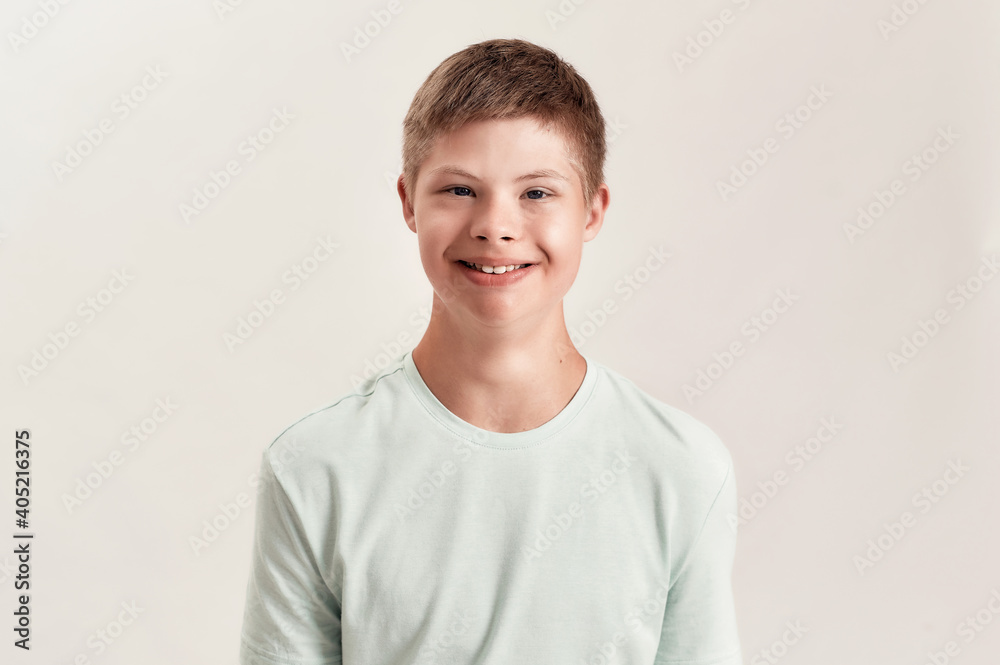Portrait of cheerful disabled boy with Down syndrome smiling at camera ...