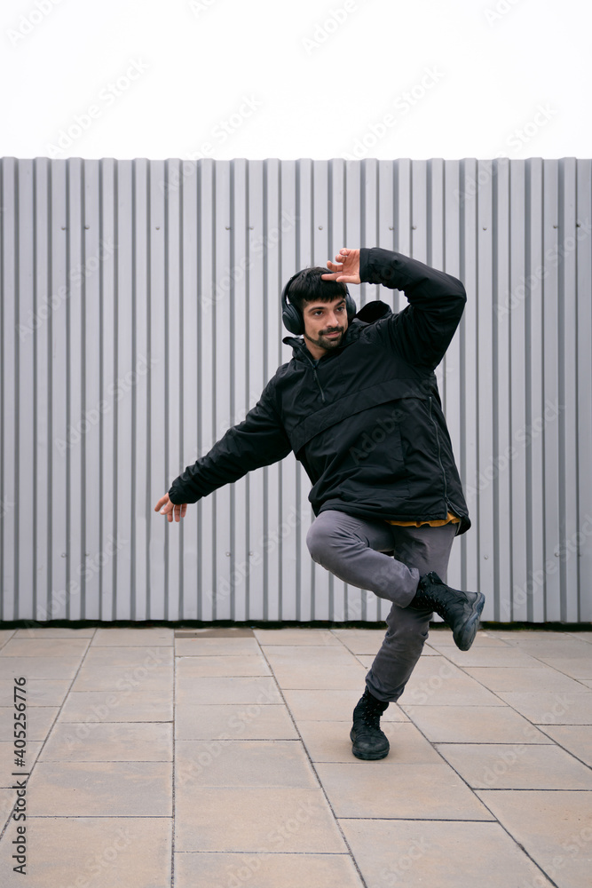 Caucasian white boy dancing with cold clothes black coat listening to music with black ...