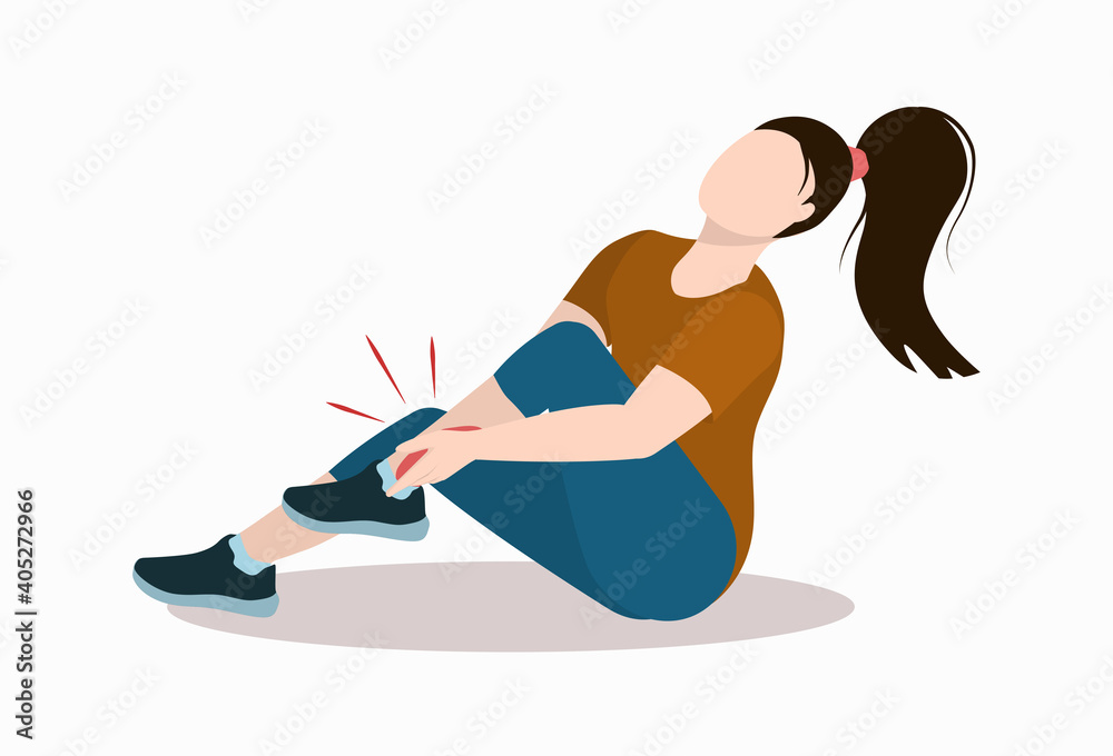 a young woman sits on the ground and holds on to her aching leg ...