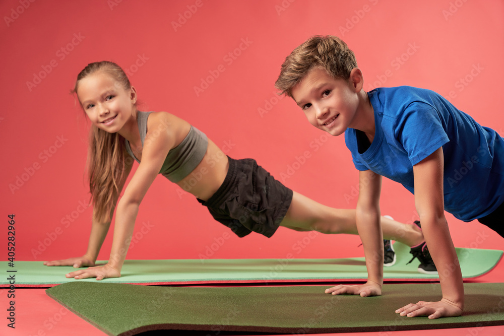 Cheerful kids doing plank exercise against red background Stock Photo ...