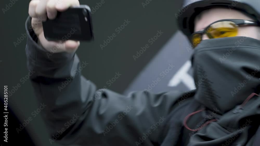Protesting young guy in helmet and black mask shooting video on phone ...