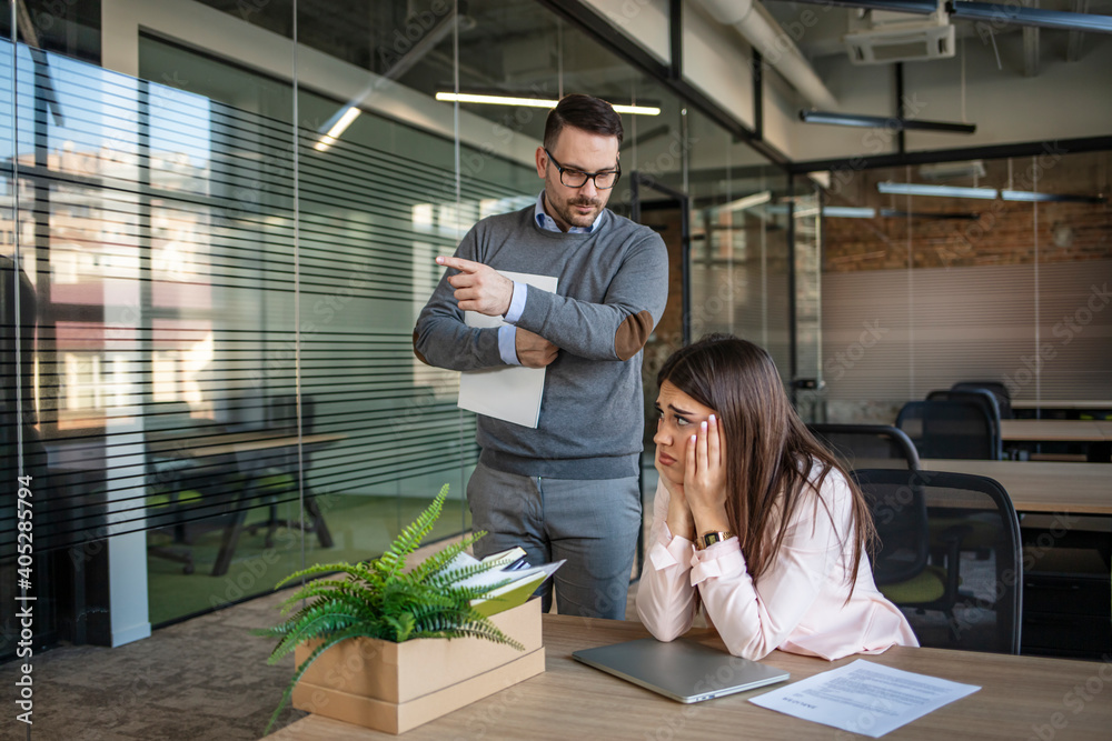 Angry boss firing upset female employee in office. Young male business ...