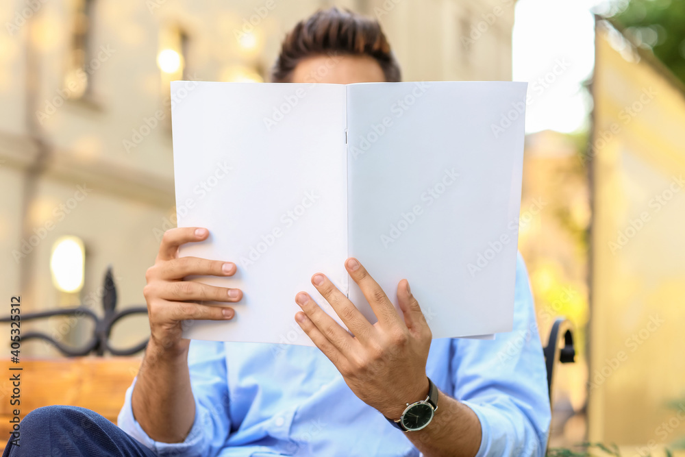 Young man reading magazine outdoors Stock Photo | Adobe Stock