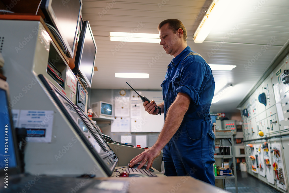 Marine Engineer working on radio communication at Engine Control room ...