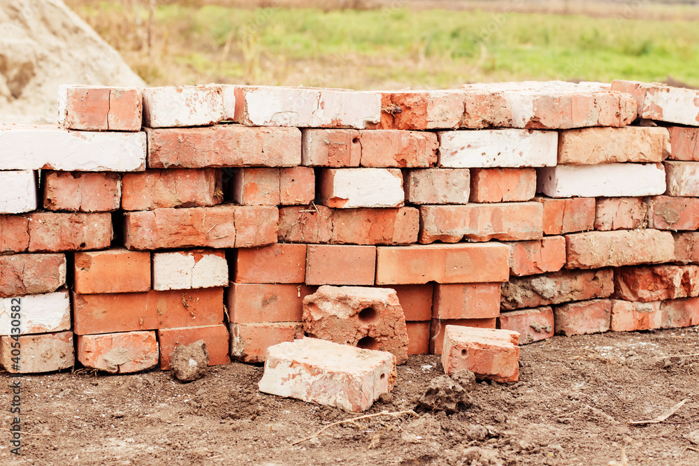 Red brick packed in stacks are stored on ground outdoors at a hardware ...