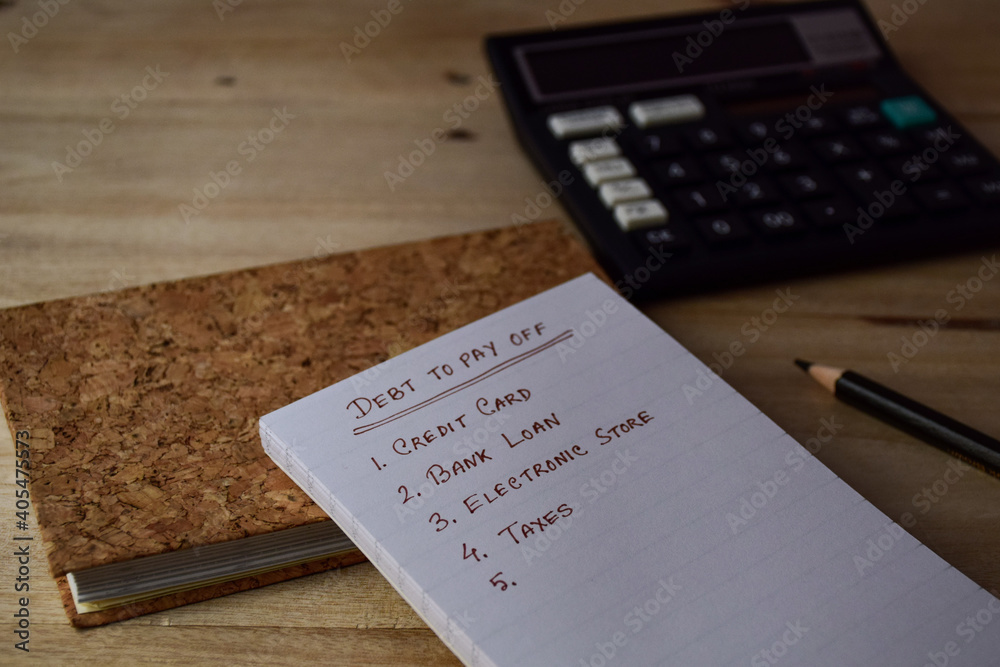 Debt list to pay off first handwritten in notepad. Office desk ...