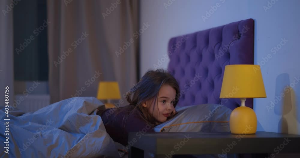 Cute little girl turning off bed lamp and falling asleep in bed Stock ...