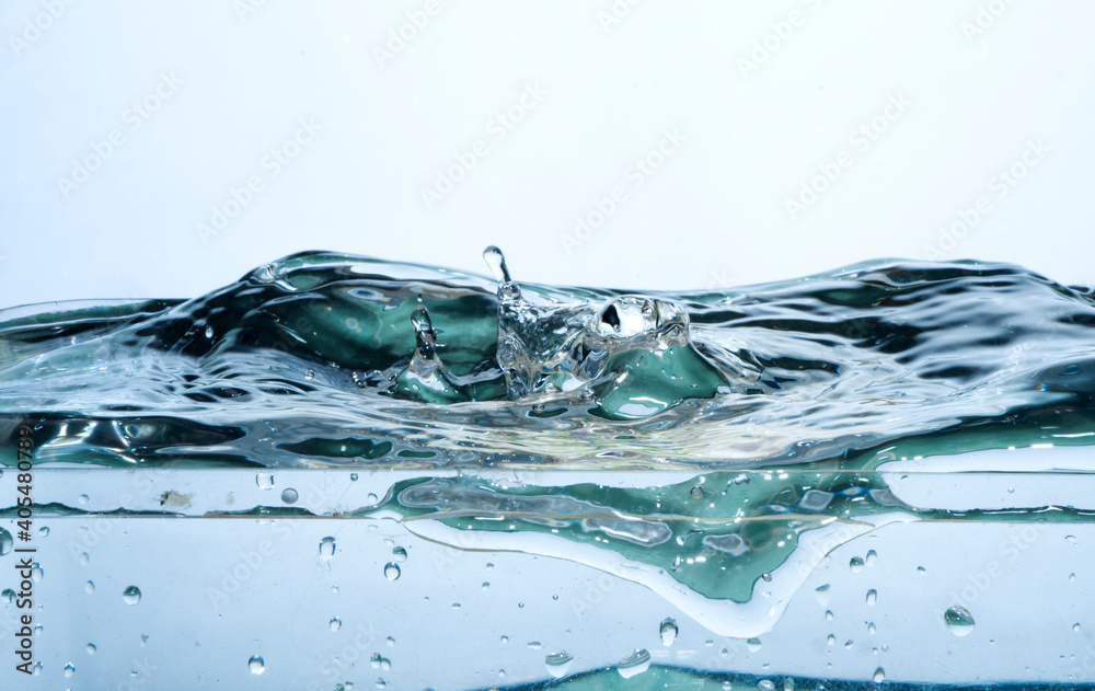 Big rain drop falls on a wavy water surface with a lot of waves ...