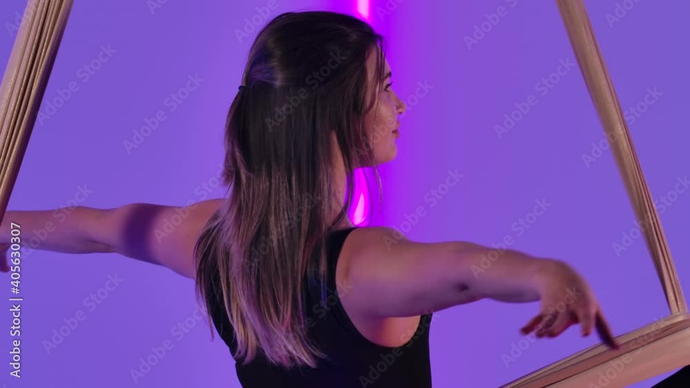 Flexible female aerial gymnast performs rotations and splits on aerial ...