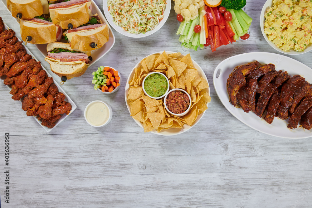 Party food spread with wings, ribs, potato salad, tortilla chips ...