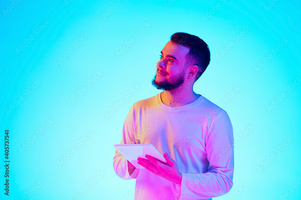 Scrolling tablet. Caucasian man's portrait with device on blue studio ...