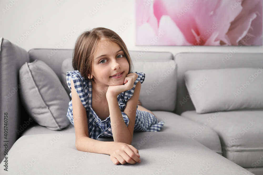 Cute little girl lying on sofa in room Stock Photo | Adobe Stock