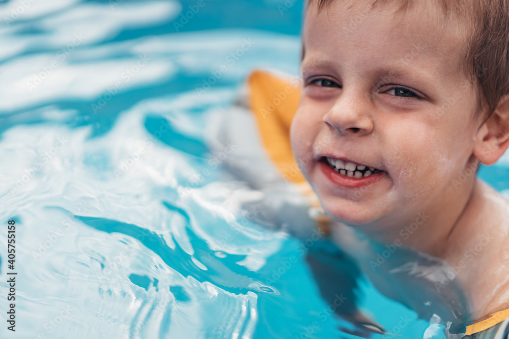 Baby boy swims independently in the pool. Little child boy learning how ...