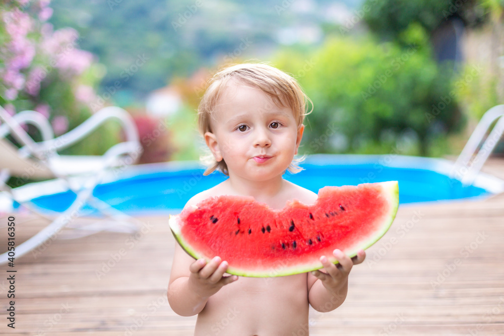 Toddler child eating watermelon near swimming pool during summer ...