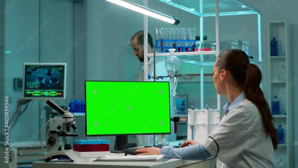 Scientist sitting at desk working on personal computer with mock-up ...