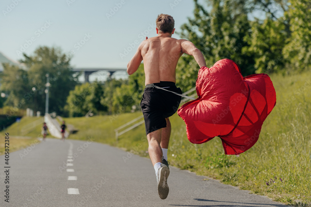 Rearview of an attractive shirtless young man running with a resistance ...