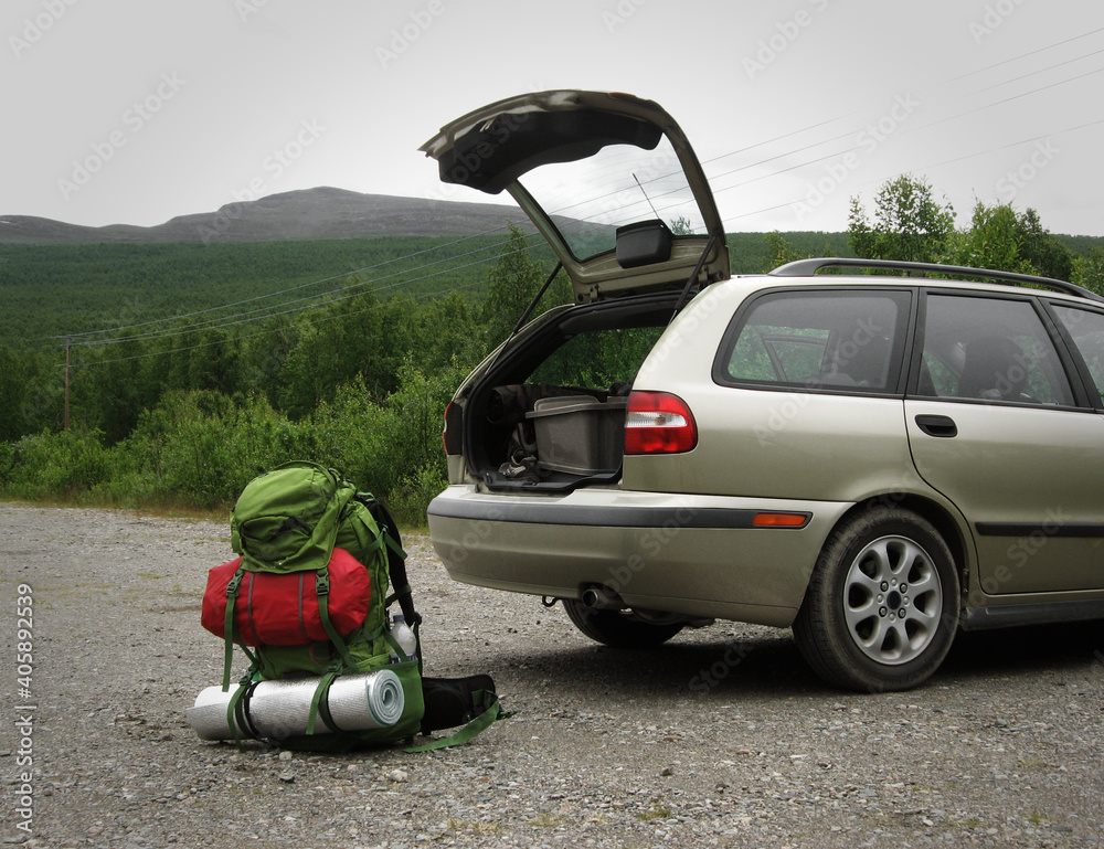 Green full-packed backpack (rucksack) behind a station wagon car with ...
