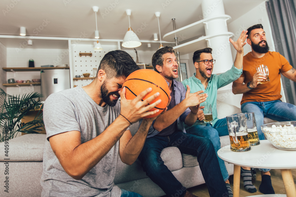 Happy friends or basketball fans watching basketball game on tv and ...