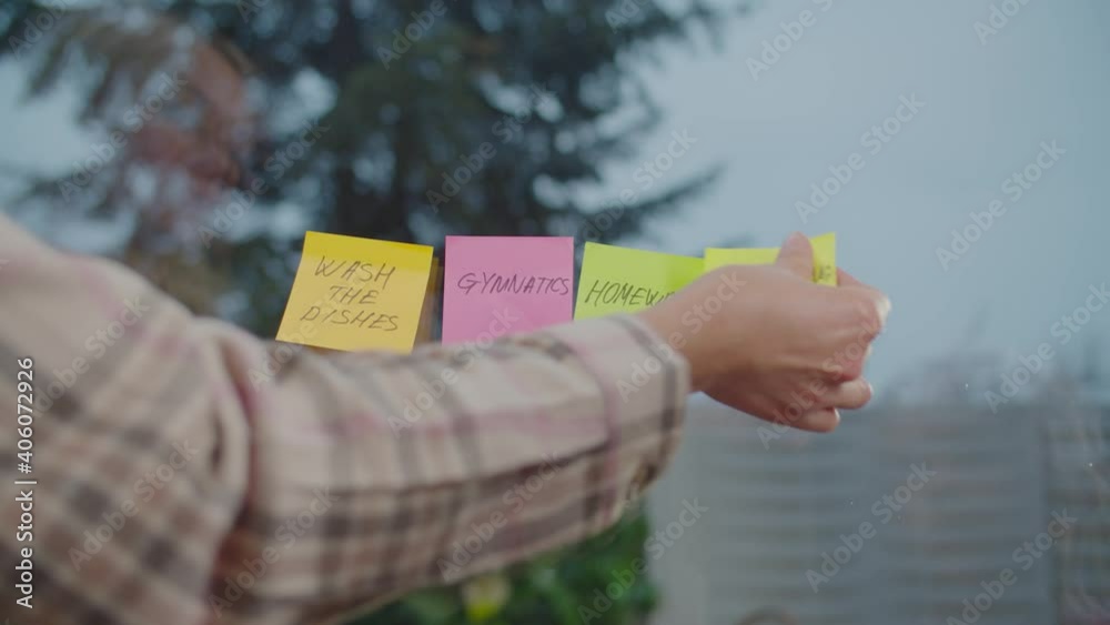 Close-up human hands attaching adhesive notes with written household ...