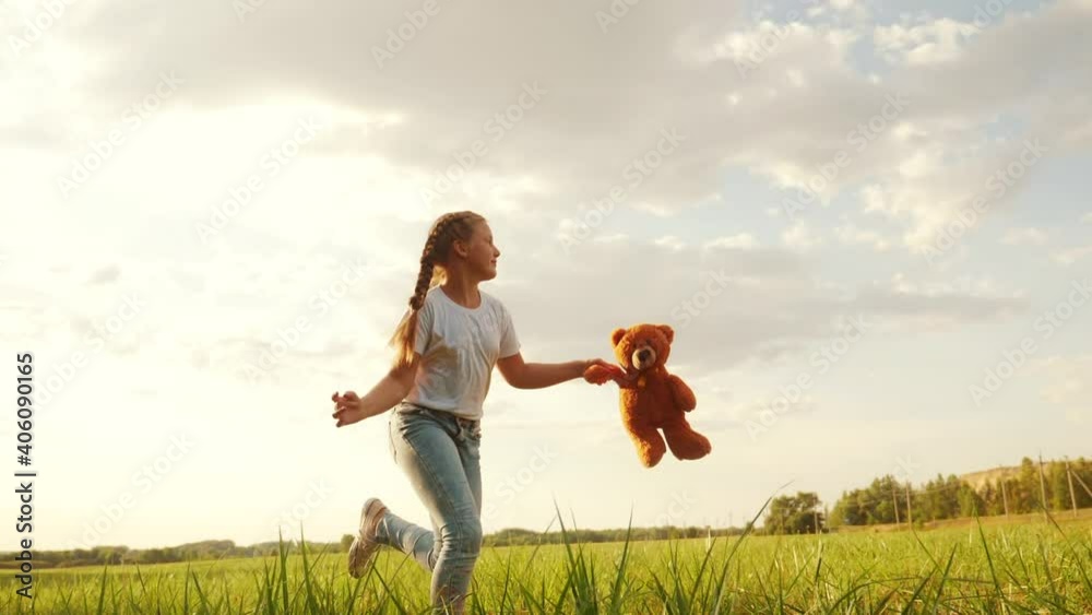 little girl with a teddy bear run in the park on the grass. happy ...
