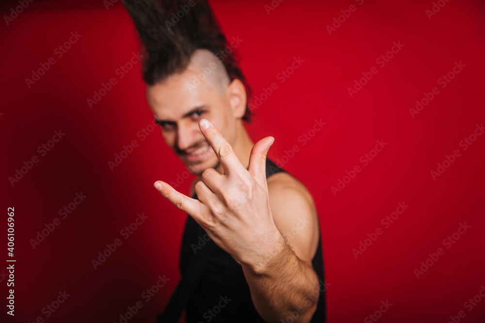 Punk with black electric guitar, mustache and big mohawk showing horn ...