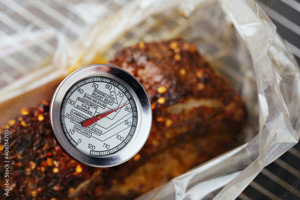 Thermometer measuring temperature of meat in sleeve. Inscription in ...