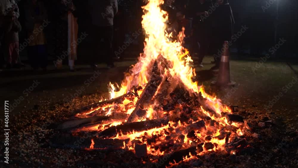 Men women families standing around giant blazing wood fire on lohri ...