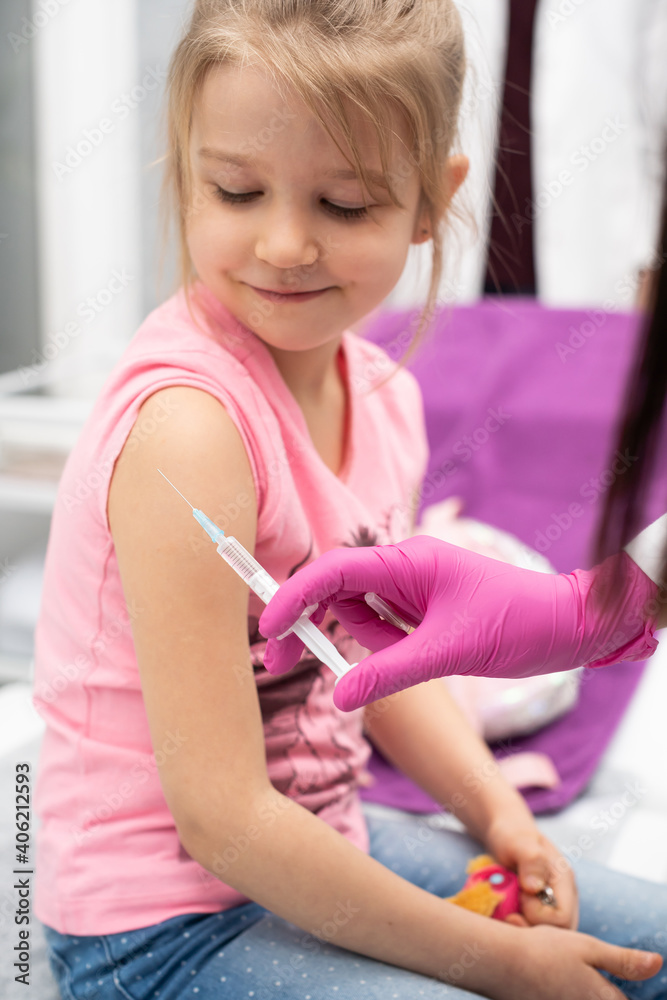 The doctor is giving a little girl an injection. The child stares in a ...