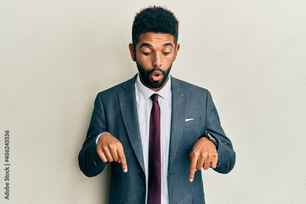 Handsome hispanic man with beard wearing business suit and tie pointing ...