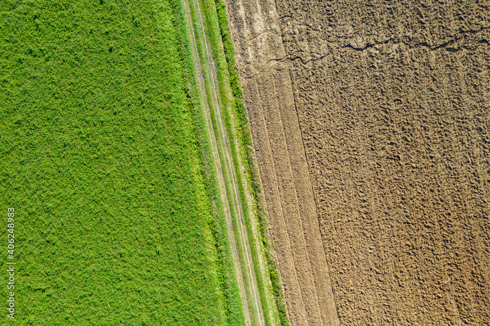 Aerial view of two fields, a cultivated and arid one on the right and a ...