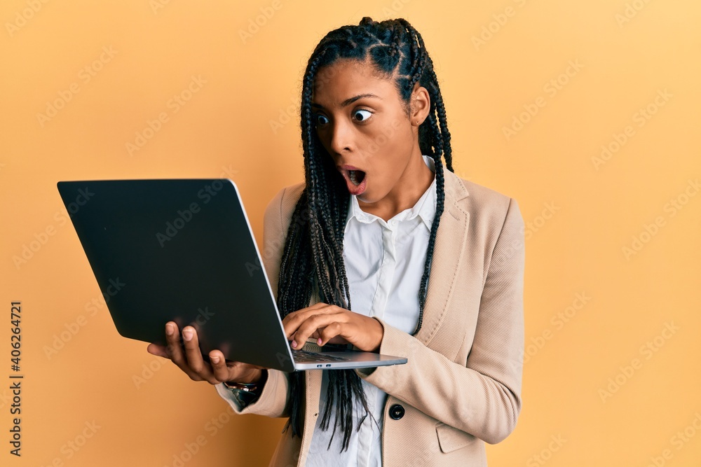 African american woman working using computer laptop afraid and shocked ...