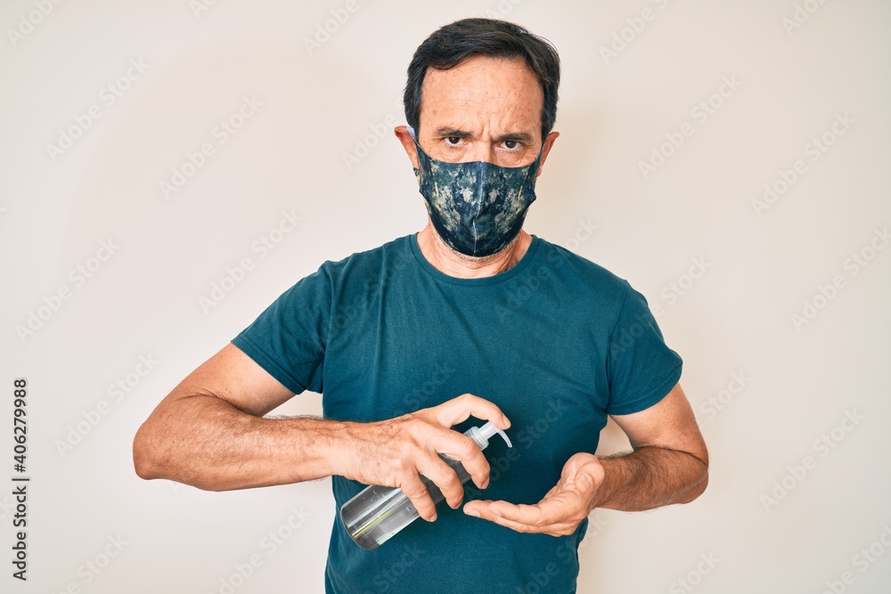Middle age hispanic man wearing covid-19 protection mask using hand ...