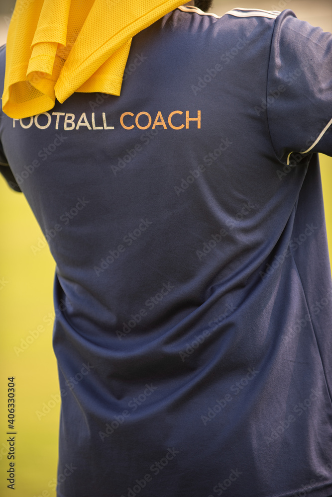 Male Youth Football Coach Standing And Watching His Team Playing In A School Tournament On A