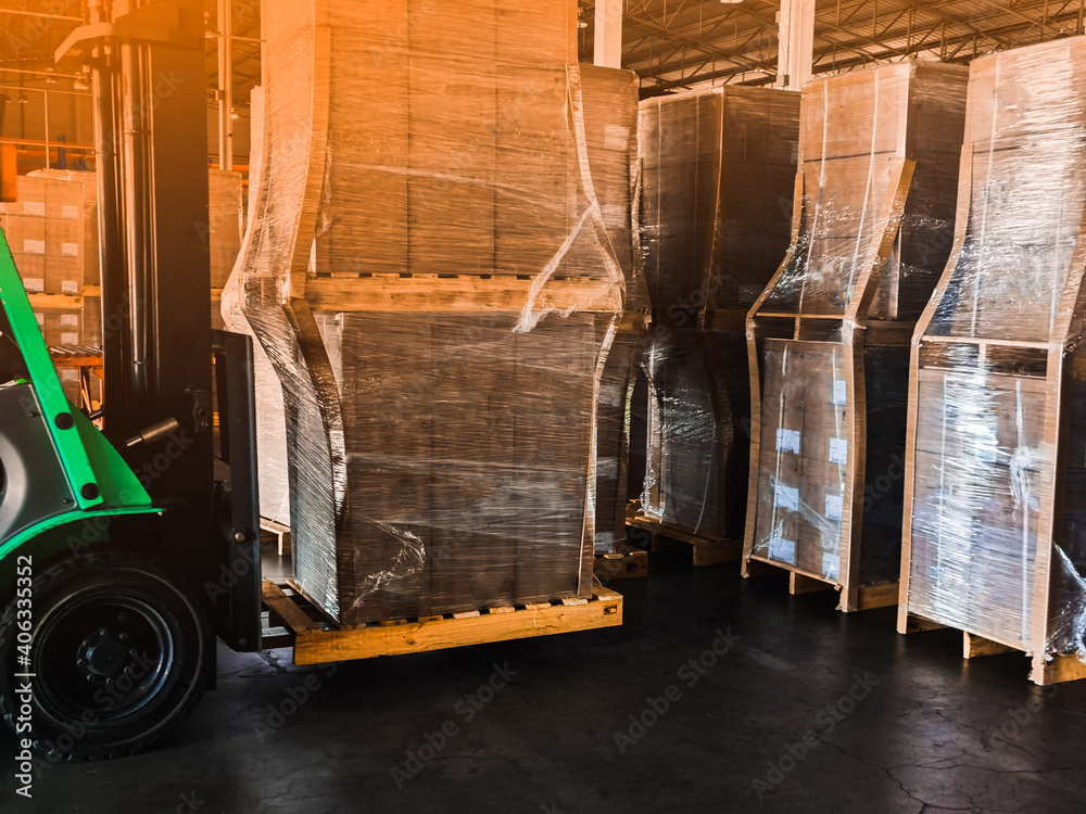 Worker driving forklift loading shipment carton boxes goods on wooden ...
