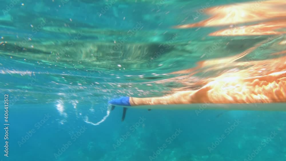 Underwater view of paddle-board bottom and paddle sailing in tranquil ...