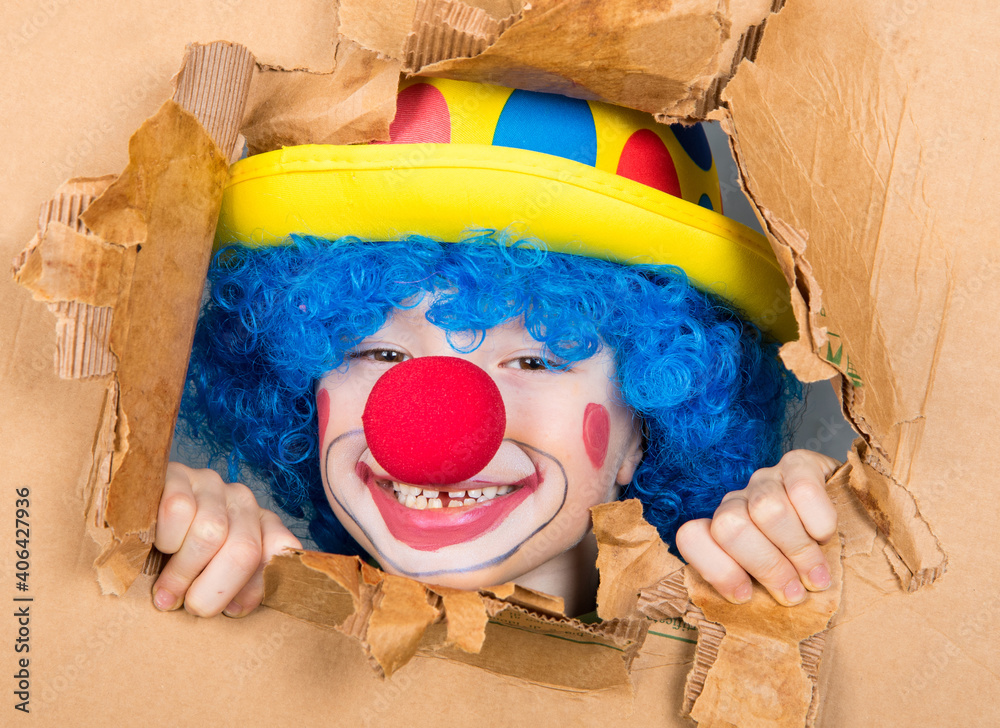 young child dressed as a clown with wig and fake nose has fun watching ...